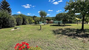 Um parque com quadra de basquete, árvores e um edifício ao fundo.