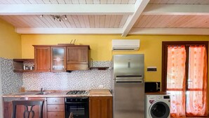 Uma cozinha compacta com fogão a gás, forno, geladeira de aço inoxidável e máquina de lavar.