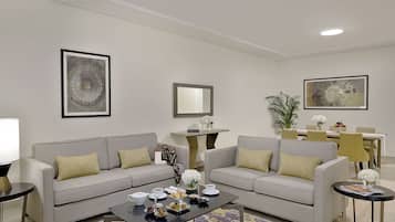 Uma sala de estar moderna com dois sofás, uma mesa de centro e uma área de jantar com cadeiras e mesa.