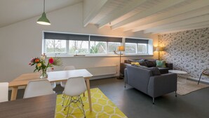 Uma sala de estar moderna com um sofá, uma mesa de jantar e um abajur.