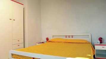 Quarto com cama, mesa de cabeceira, guarda-roupa e escrivaninha.