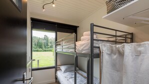 Quarto com beliche, janela, porta e luminária no teto.