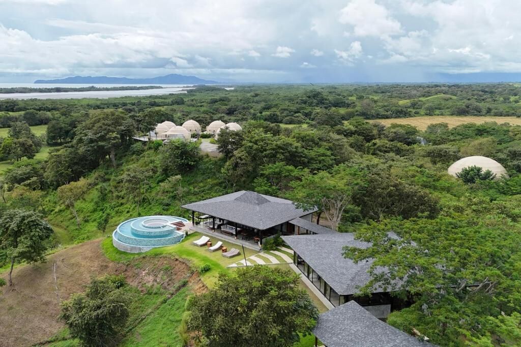 Um resort com piscina, espreguiçadeiras e vista para a paisagem ao redor.