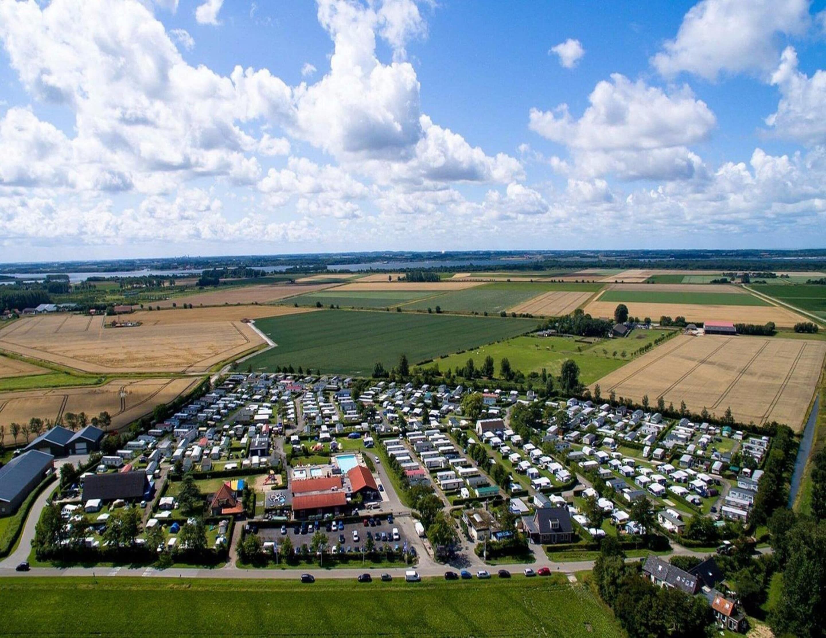 Vista aérea de uma área residencial com várias casas e um edifício central com telhado vermelho.