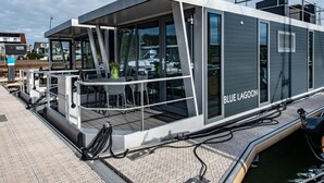 Uma estrutura moderna flutuante chamada Blue Lagoon, com área de estar coberta ao ar livre e grandes janelas.