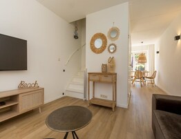 Uma sala de estar moderna com televisão de tela plana, uma mesa redonda e uma escada que leva a uma área de jantar.