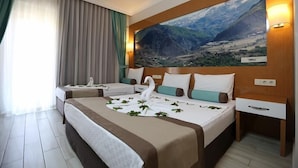 Quarto de hotel com uma cama grande, duas mesas de cabeceira, um criado-mudo e uma TV fixada na parede.