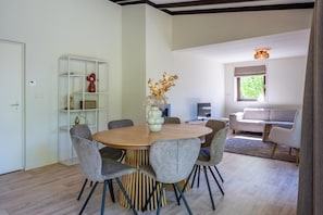 Uma sala de jantar moderna com uma mesa redonda, cadeiras estofadas cinzas e uma estante branca com objetos decorativos.