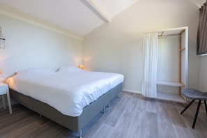 Quarto com cama grande, mesa de cabeceira, cadeira e guarda-roupa embutido.