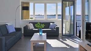 Sala moderna com sofá, mesa de centro e vista para a água.