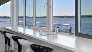 Cozinha moderna com grandes janelas para um lago, uma cafeteira e dois banquetes.