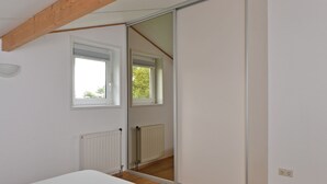 Quarto com cama, janela, radiador e porta deslizante.