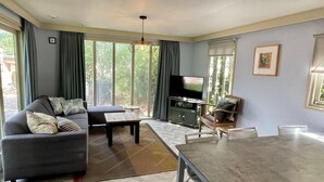 Uma sala de estar moderna com sofá, mesa de centro, TV e mesa de jantar.
