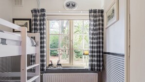 Quarto com janela, radiador, cama e quadro na parede.