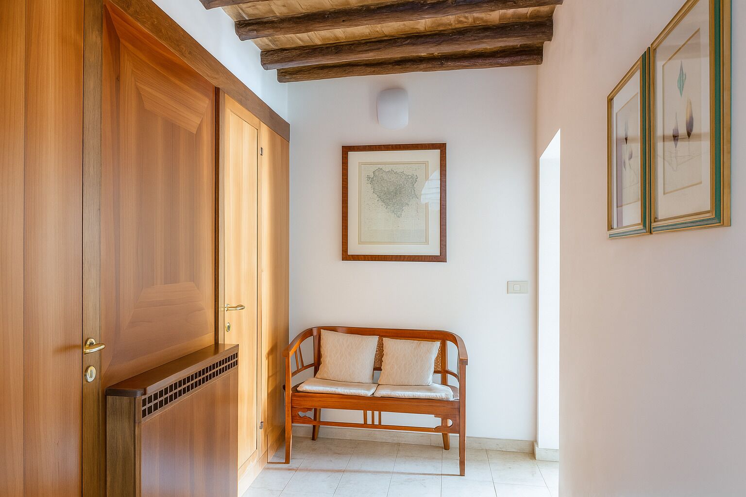 Um corredor com portas de madeira, um banco de madeira e quadros nas paredes.