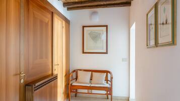 Um corredor com portas de madeira, um banco de madeira e quadros nas paredes.