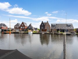 Um canal com casas numa margem e barcos atracados na água.