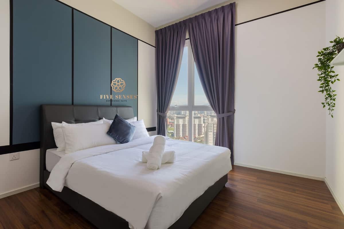 Quarto de hotel moderno com uma cama grande, vista para a cidade e um logotipo na parede.