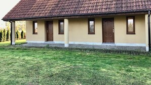 Uma casa de dois andares com telhado de telhas, varanda da frente e gramado bem cuidado.