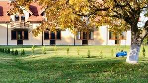 Um edifício com fachada simétrica, várias janelas e uma árvore em primeiro plano.