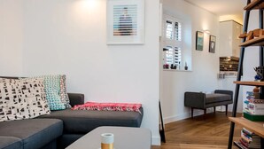 Uma sala de estar moderna com um sofá cinzento, uma mesa de centro e uma estante.