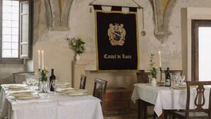 Uma área de refeições com mesas postas para uma refeição, um banner com o texto 'Castel di Luco' e um candelabro.