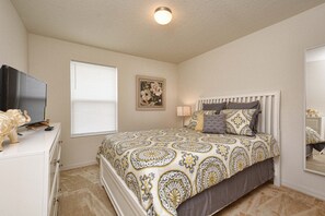 Quarto com cama, escrivaninha, cadeira, luminária e janela com persianas.
