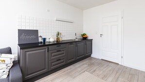 Uma cozinha moderna com armários cinza escuro, bancada preta e backsplash com azulejos brancos.