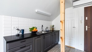 Uma cozinha moderna com armários escuros, azulejos brancos estilo metrô e bancada preta.