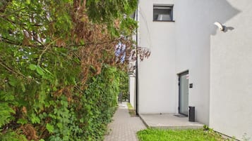 Um caminho estreito que leva a um edifício branco com uma porta e uma janela.