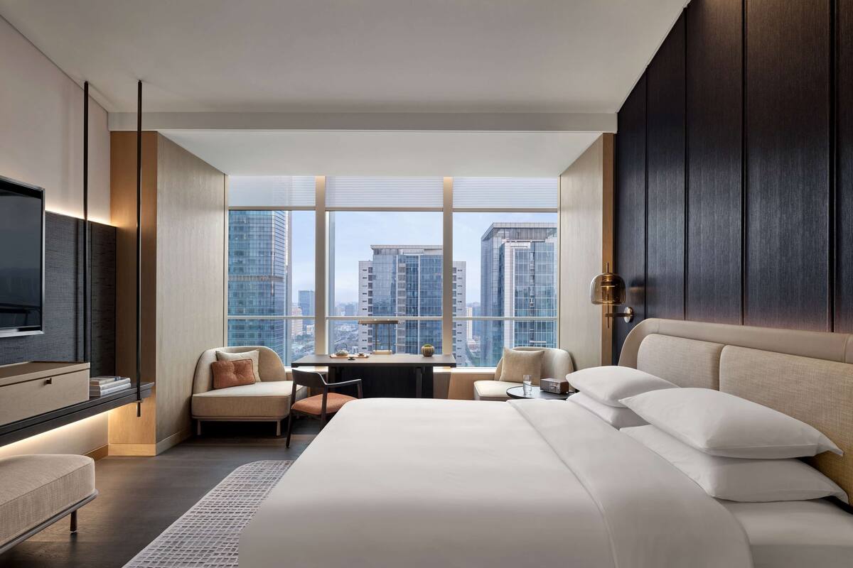 Quarto de hotel moderno com uma cama grande, uma escrivaninha e uma televisão.