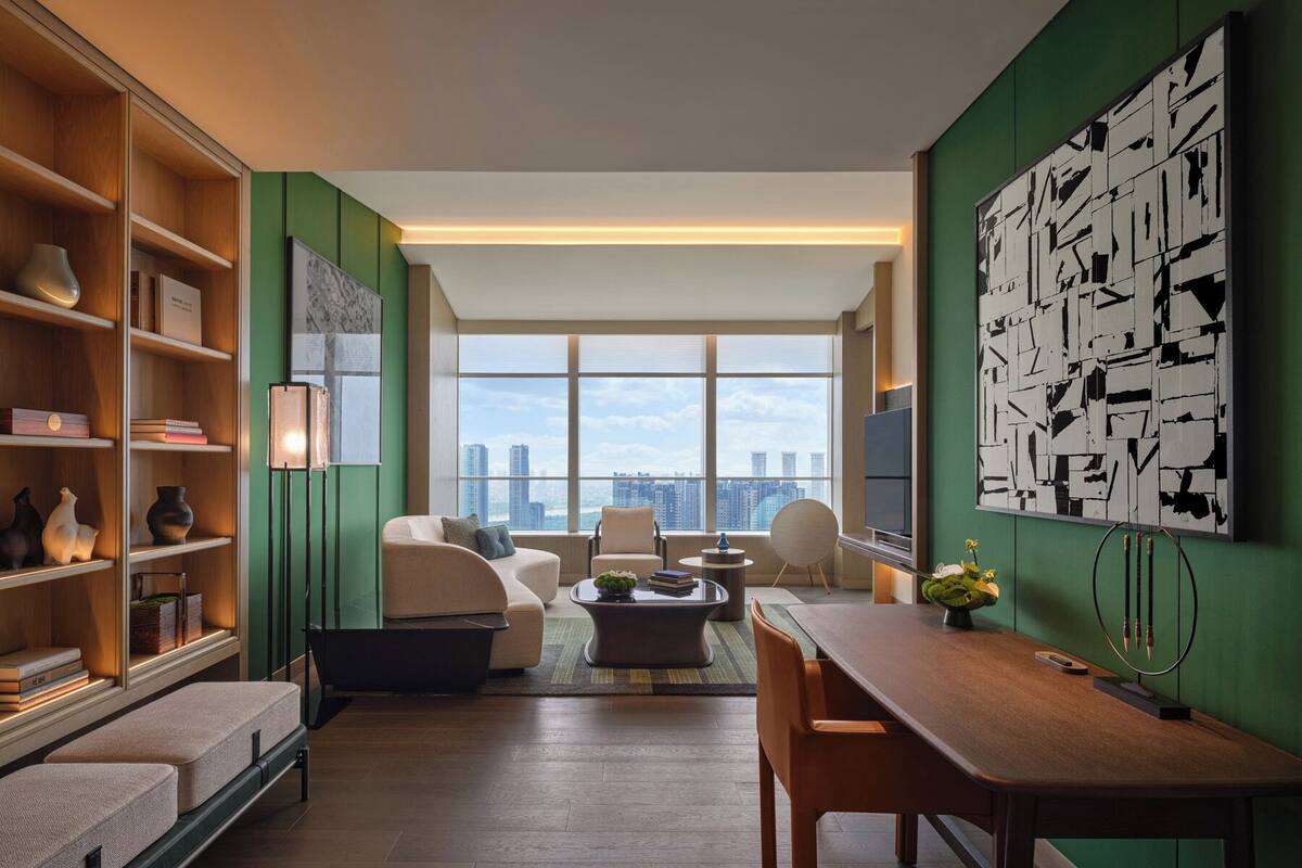 Uma sala de estar moderna com vista para a cidade, paredes verdes e um grande quadro abstrato.