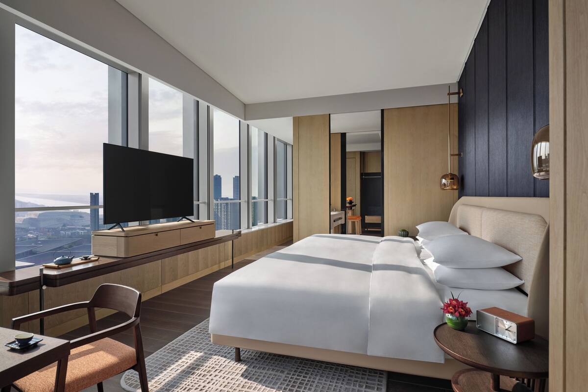 Quarto de hotel moderno com uma cama grande, uma escrivaninha e uma televisão.