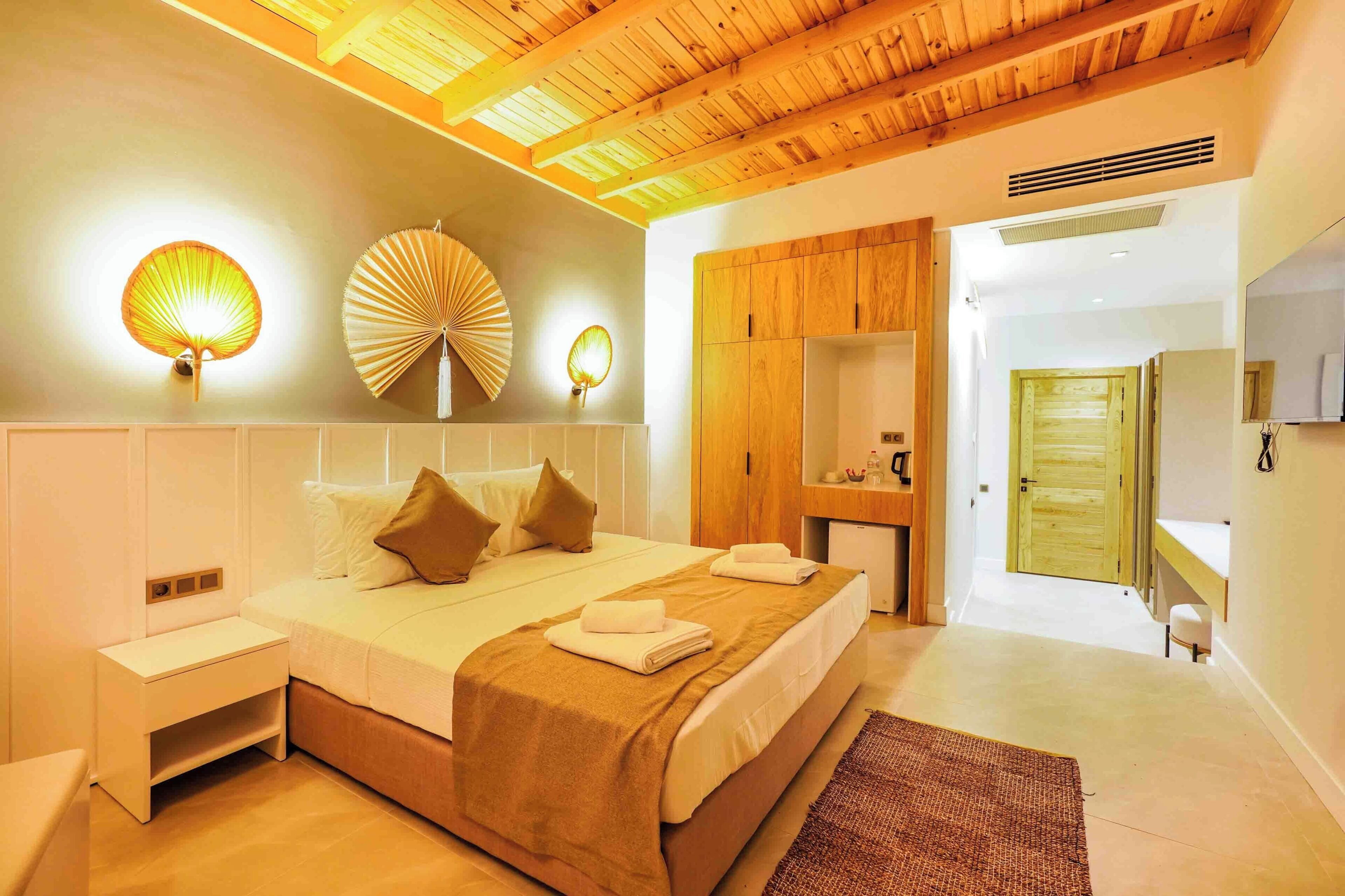 Um quarto com cama, mesas de cabeceira, teto de madeira e um espelho.