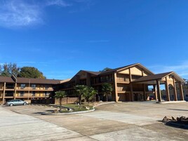 Um motel com vários andares, pátio central, área de estar externa e estacionamento.