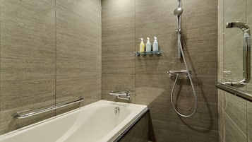 Uma casa de banho moderna com banheira, chuveiro e um prateleira com artigos de higiene pessoal.