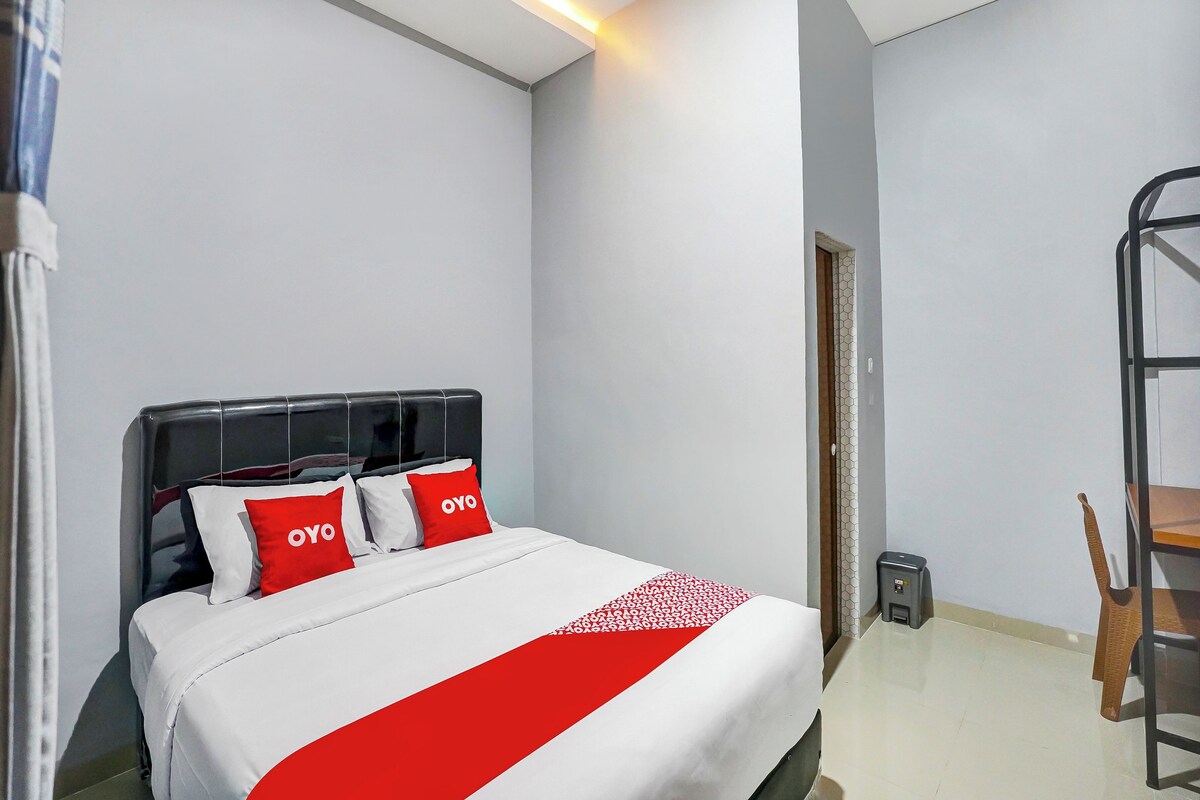 Quarto de hotel com cama, secretária, cadeira e guarda-roupa.