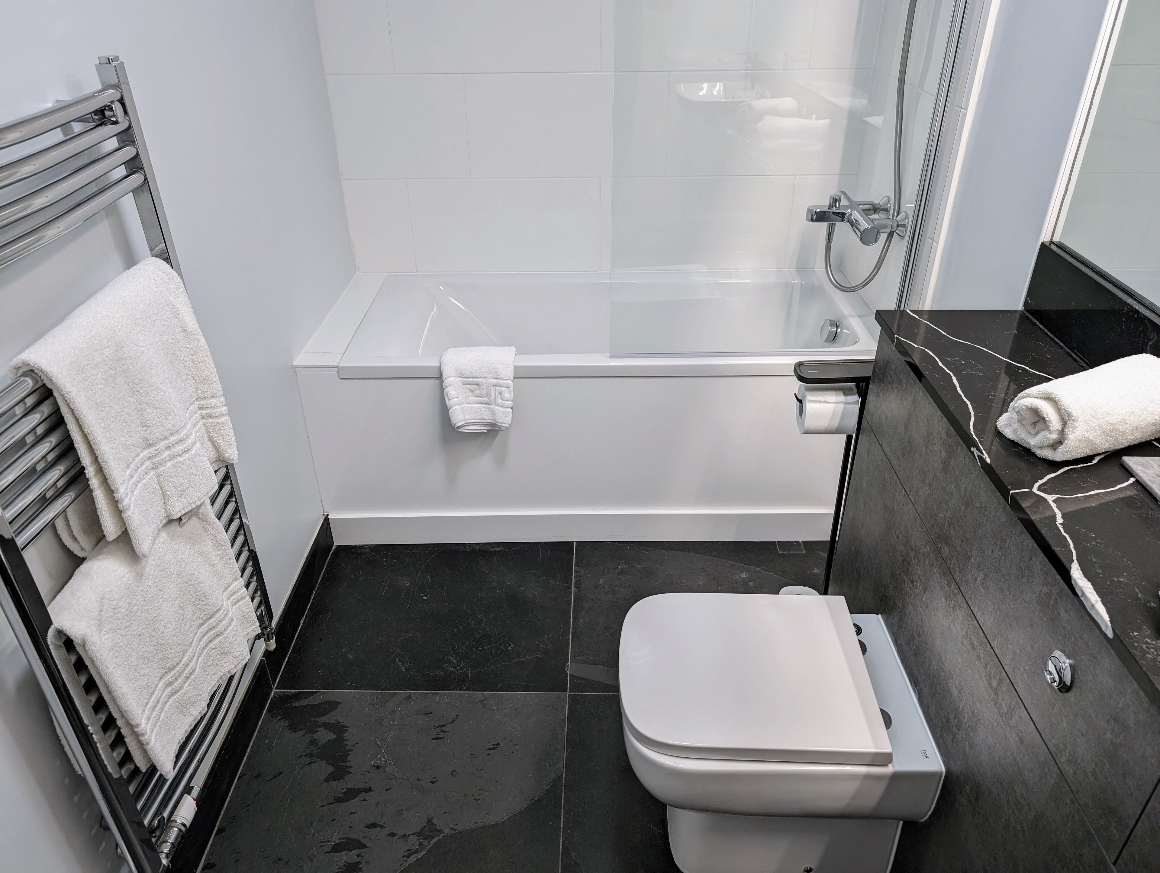 Uma casa de banho moderna com banheira, sanita e porta-toalhas.