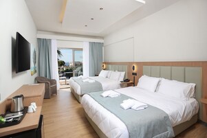 Quarto de hotel com duas camas, uma mesa, uma cadeira e uma televisão.