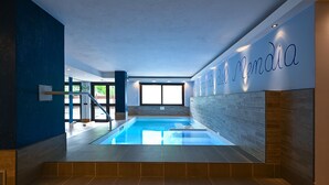 Piscina interna com vista para o exterior, uma escadaria e uma parede com o texto "La piscina del Mendaia".