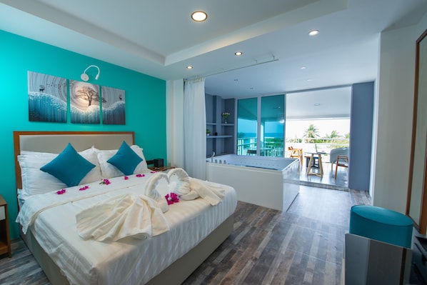Quarto de hotel moderno com uma cama grande, vista para a varanda e banheiro com banheira.