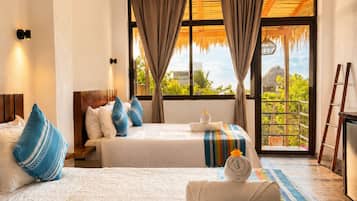 Quarto de hotel com duas camas, ventilador de teto, janela grande com cortinas e vista para o verde lá fora.