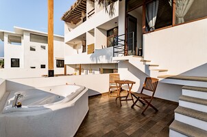 Terraço moderno ao ar livre com banheira, cadeiras de madeira e uma escadaria.