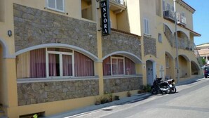 Um hotel com fachada de pedra, varandas e uma motocicleta estacionada.