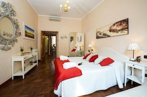 Quarto de hotel com uma cama grande, mesa de cabeceira, espelho e um quadro na parede.