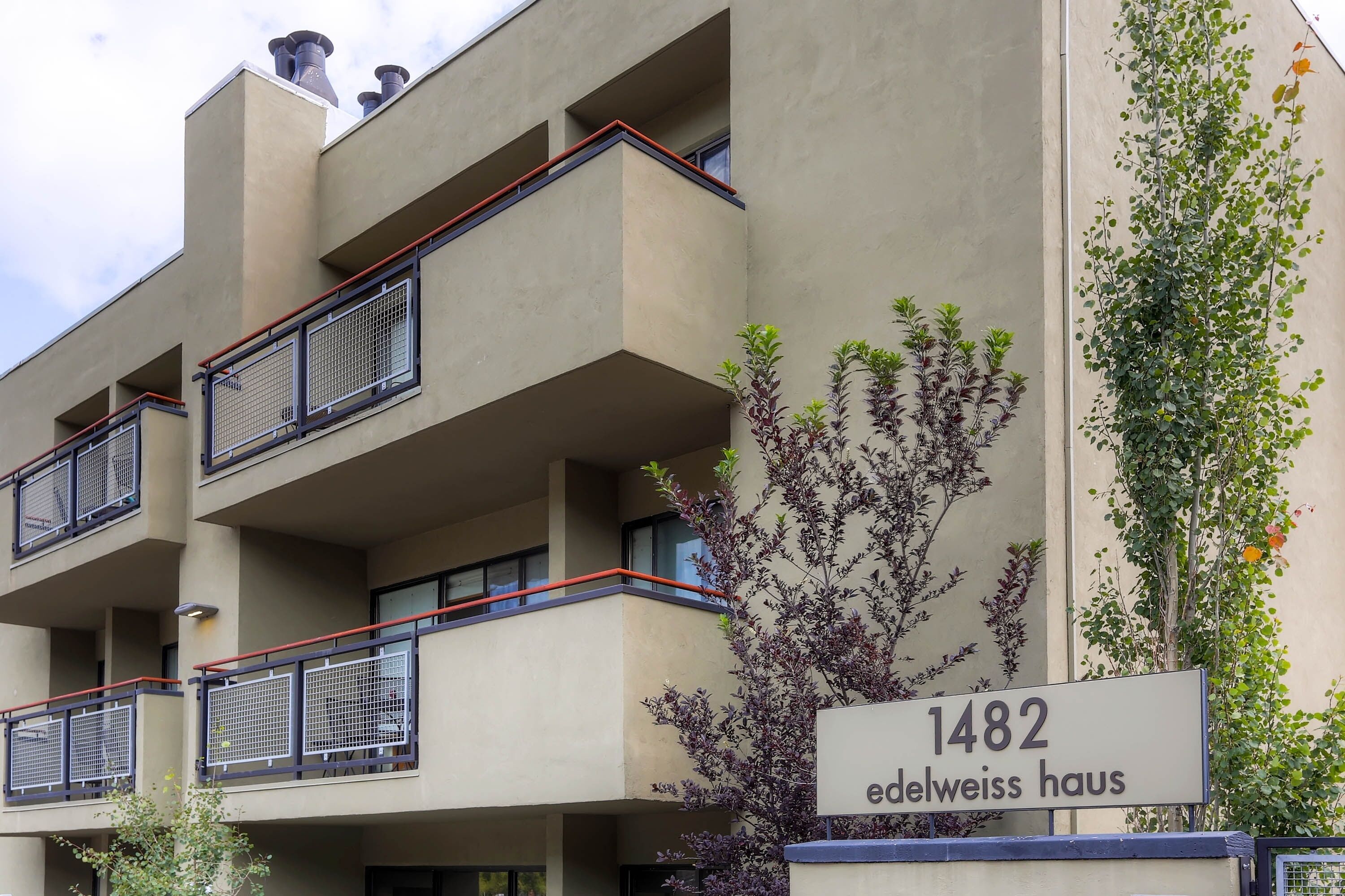 Um edifício de vários andares com varandas e uma placa indicando '1482 Edelweiss Haus'.