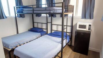 Quarto em dormitório com beliches, micro-ondas e pequeno frigorífico.
