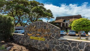 Placa de pedra com 'Madinah Surf' e '12 South Kihei Road' indicando um local.