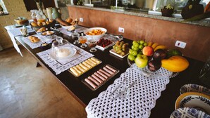 Uma mesa de buffet com diversos alimentos e um jogo de toalha decorativo em crochê.