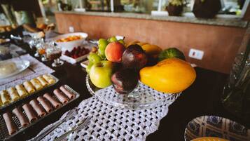 Uma mesa com uma tigela de frutas, doces e um jogo americano de crochê.